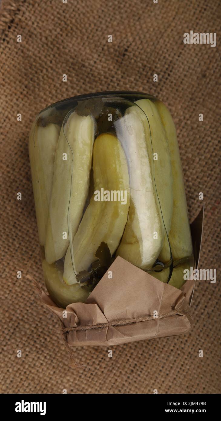 A vertical shot of canned cucumbers on a fabric texture background ...
