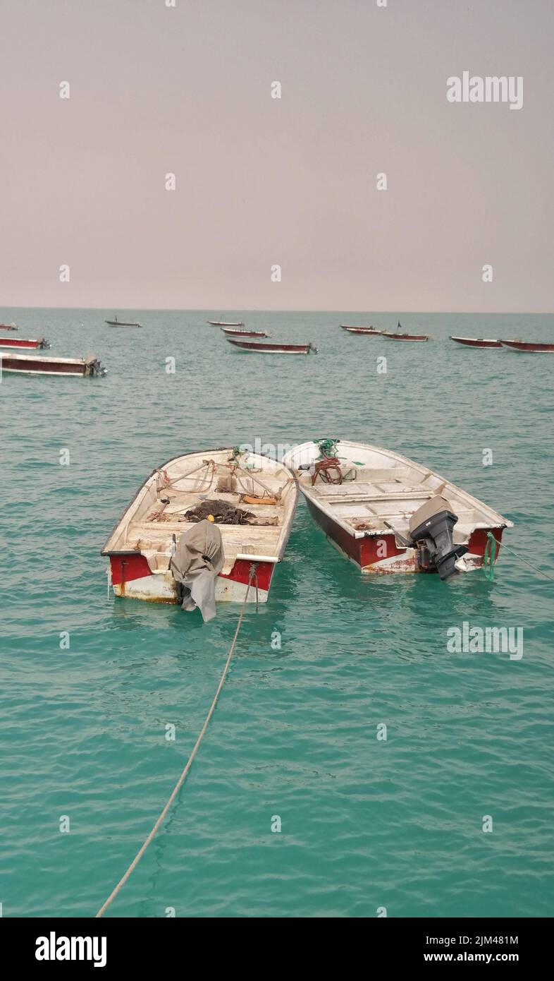 A vertical shot of the boats in the sea with a cloudless sky in the ...
