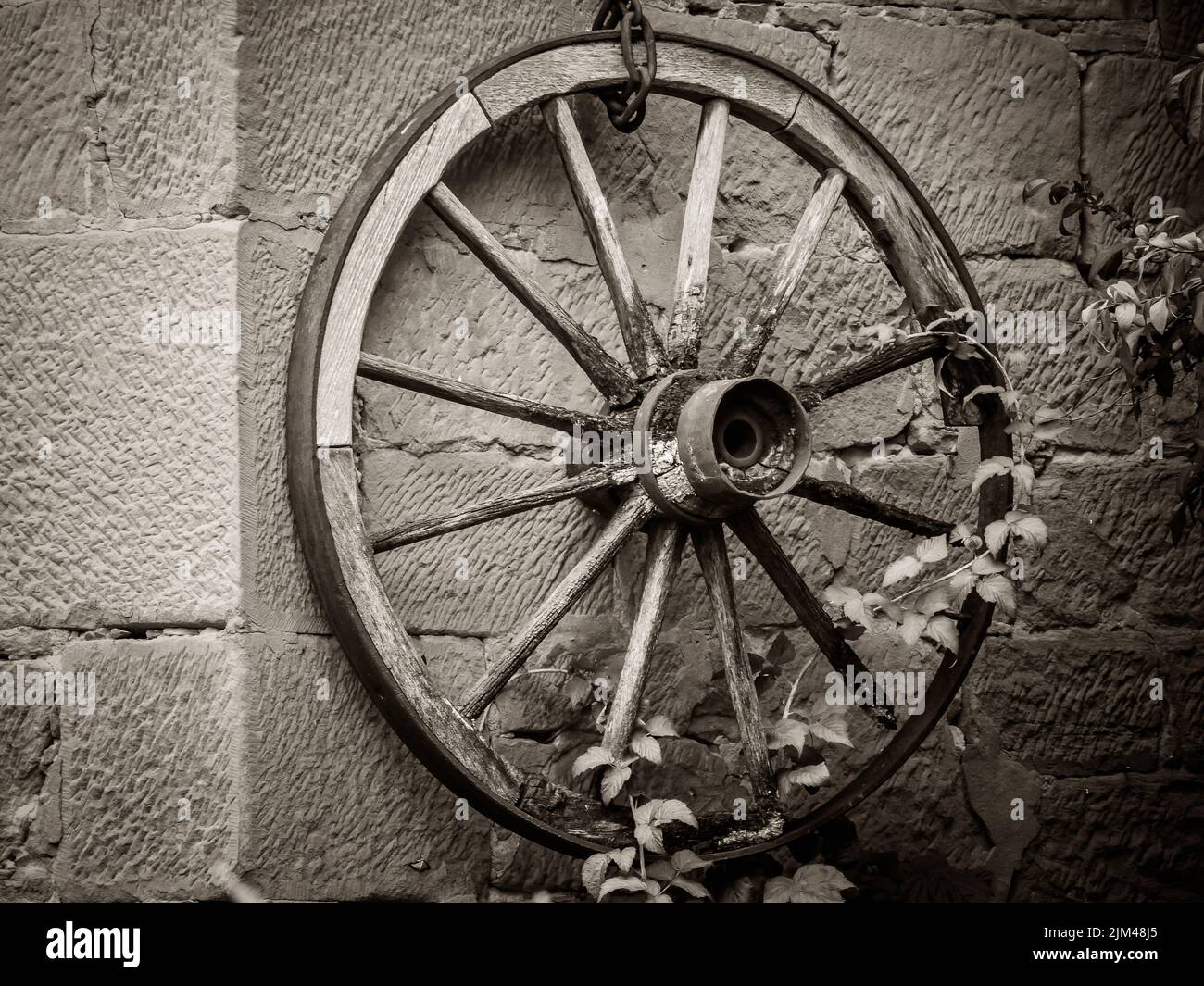 An old wheel hanging on the building Stock Photo - Alamy