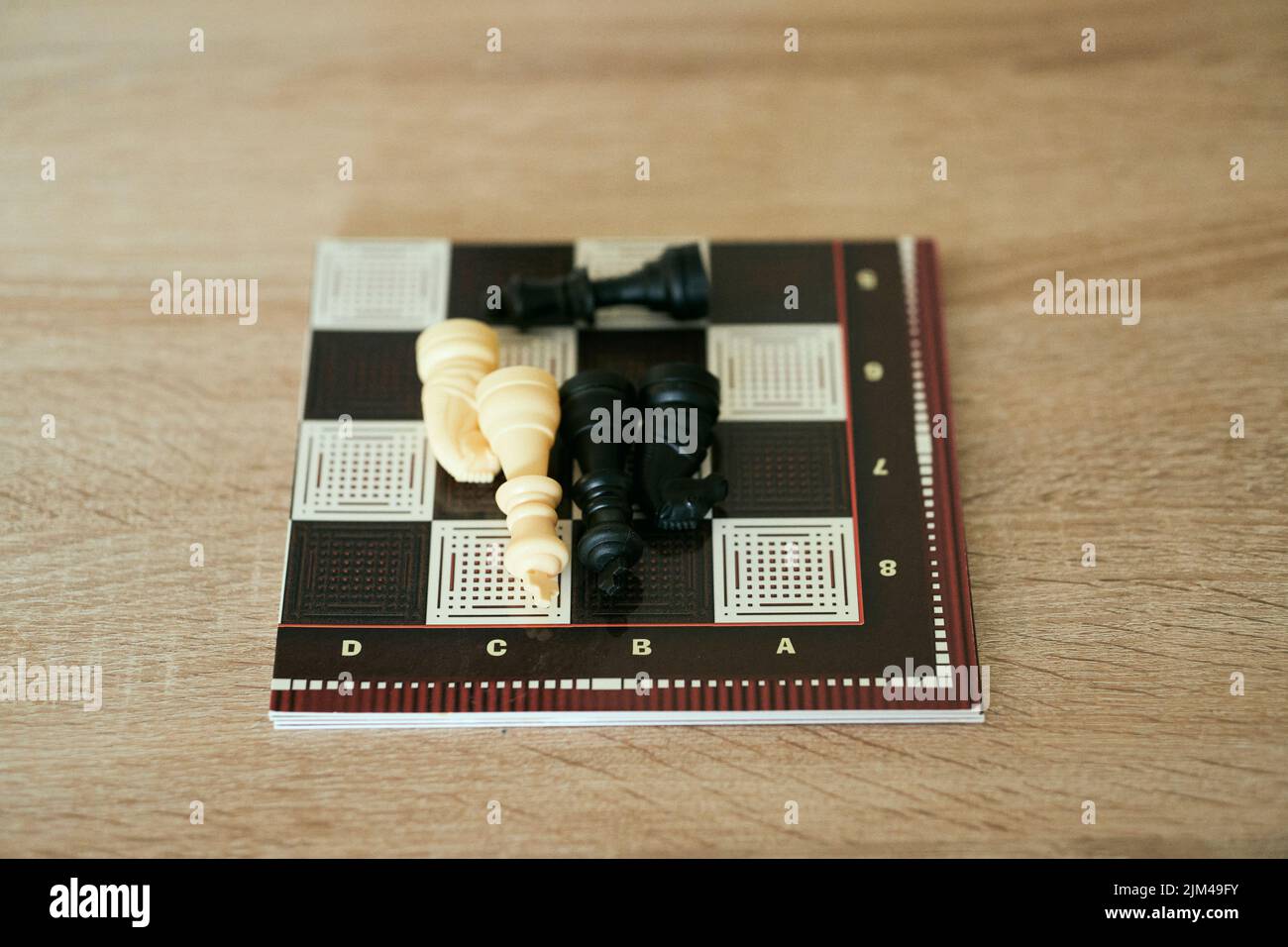 A closeup shot of fallen black and white chess figures on the board ...