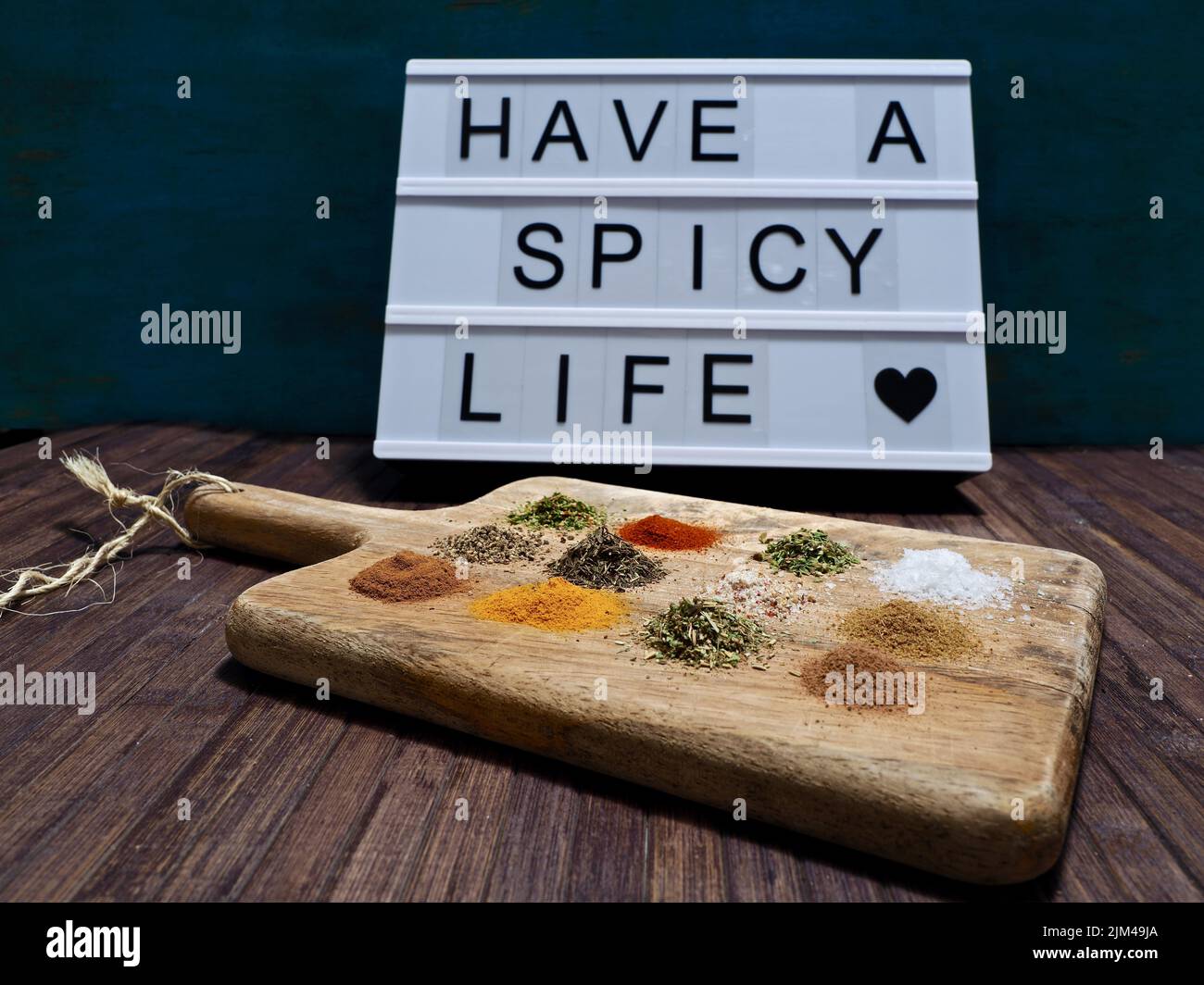 wooden tray with very colorful spices on top of it and a sign behind ...