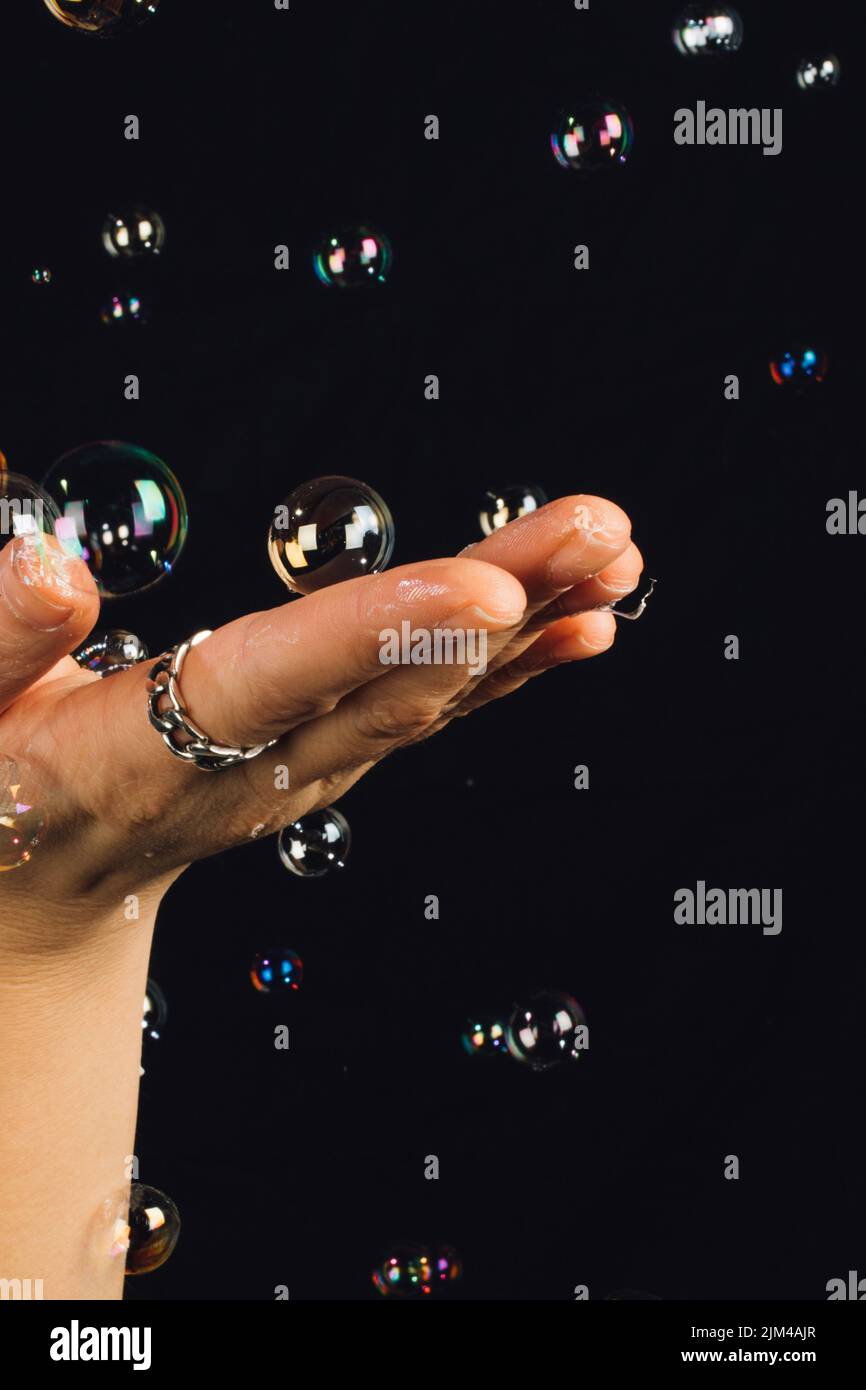 woman holding up flattened hand gesturing to floating, touchable bubbles on black background ...