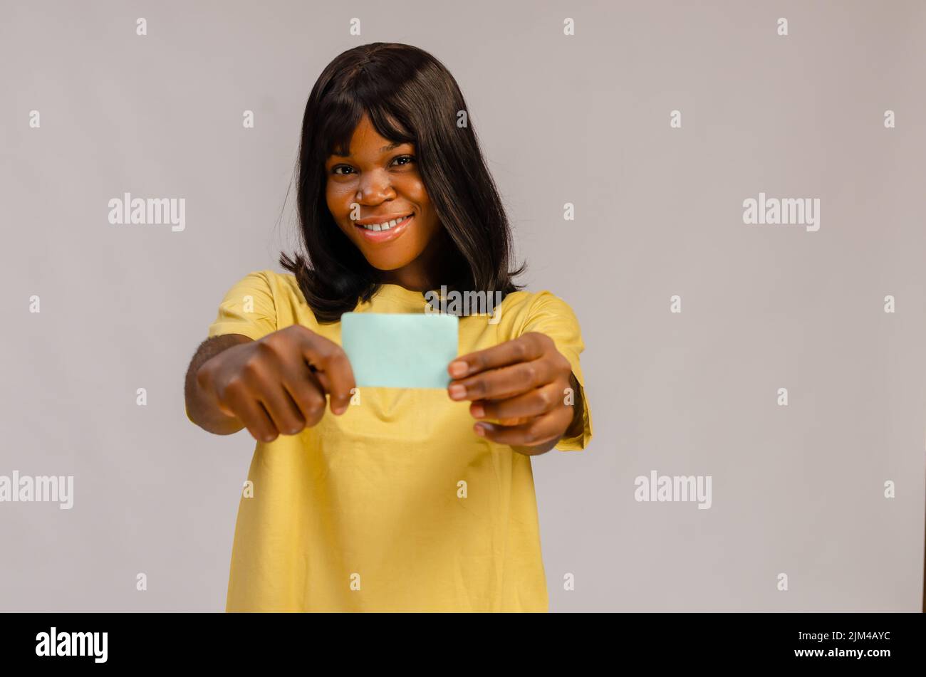An African smiling girl in stylish clothes holding offering a blank ...