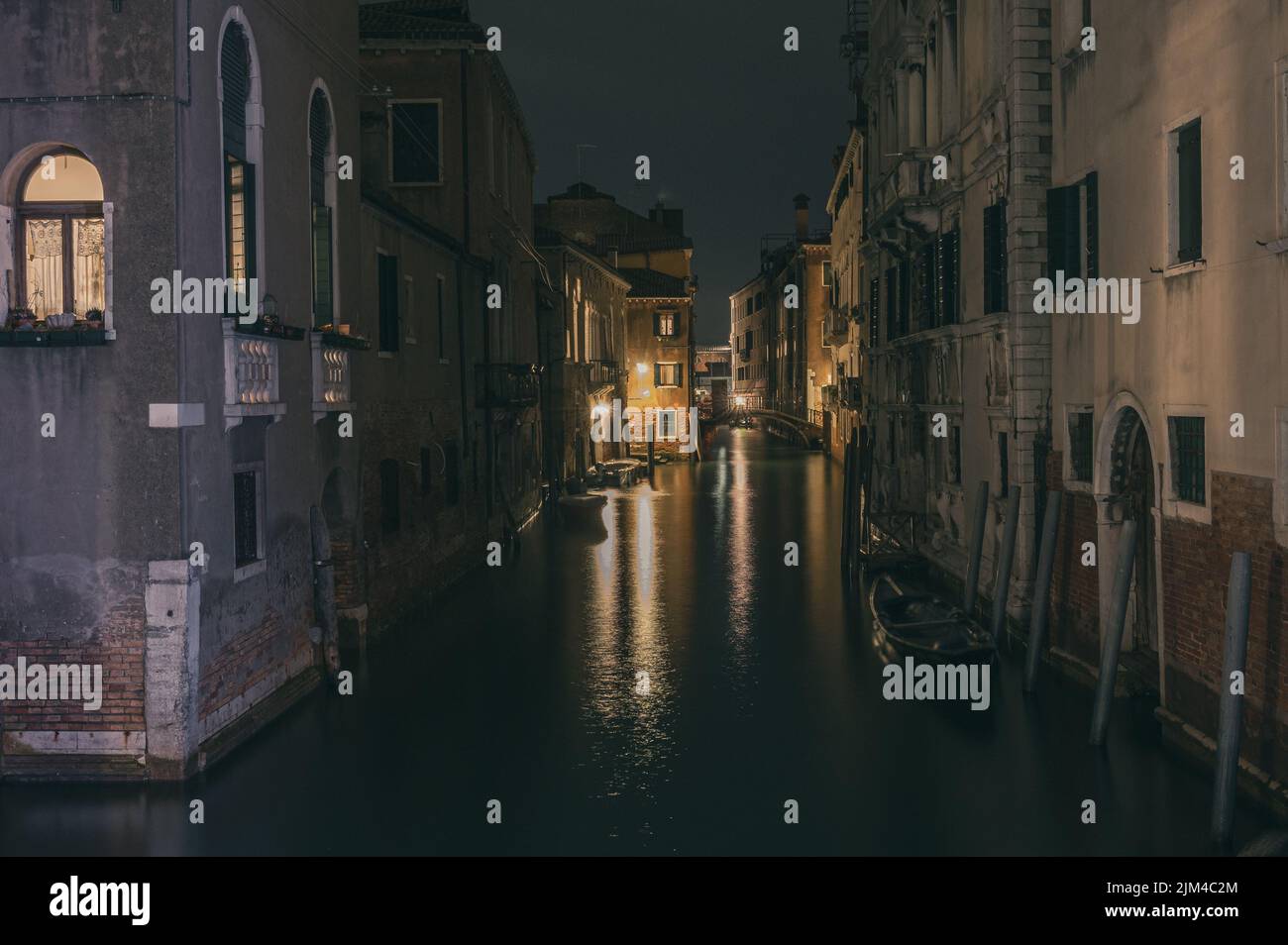 The Gondola canal with reflection surrounded by buildings in night ...