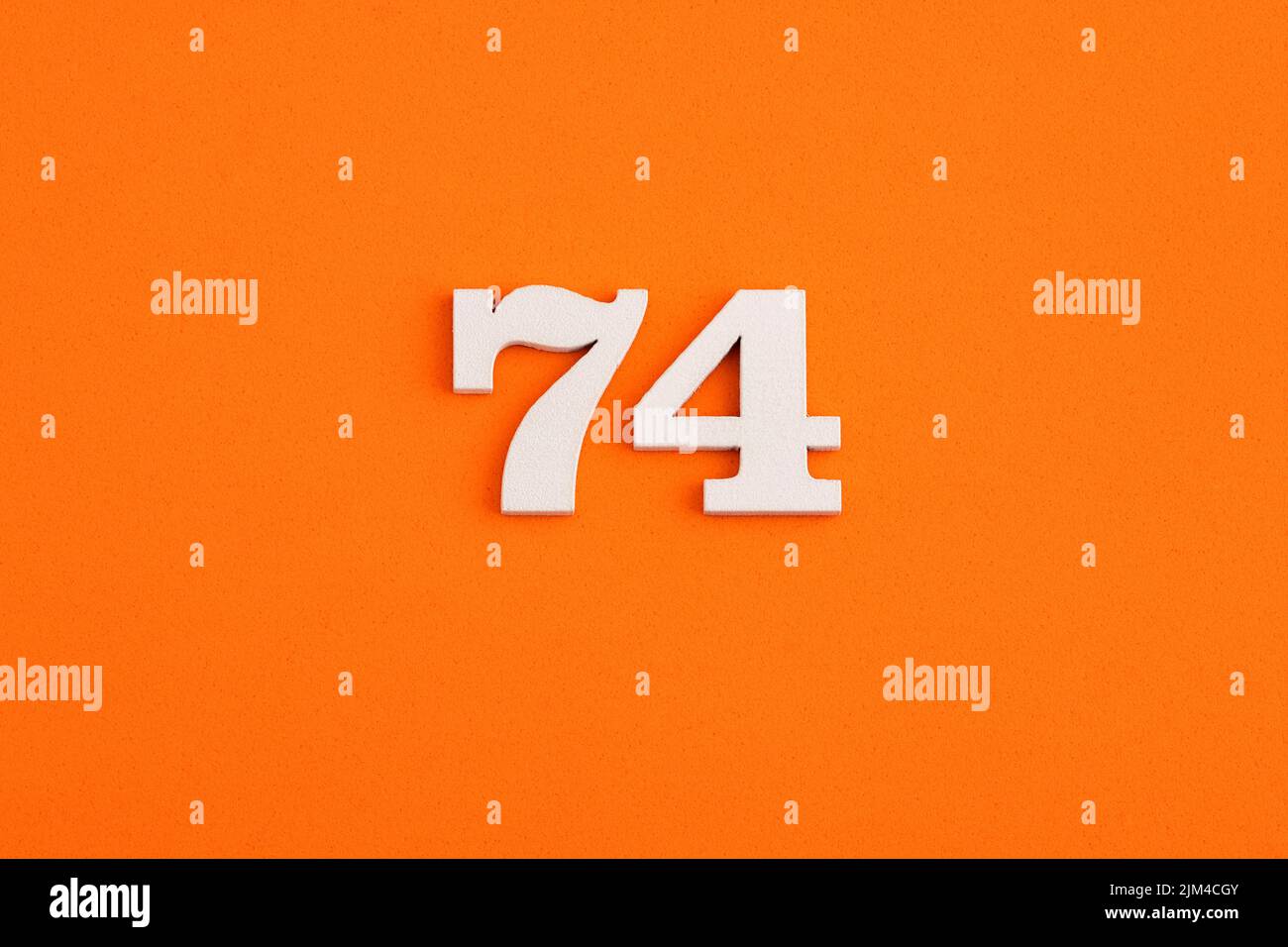 White wooden number 74 on eva rubber orange background Stock Photo - Alamy