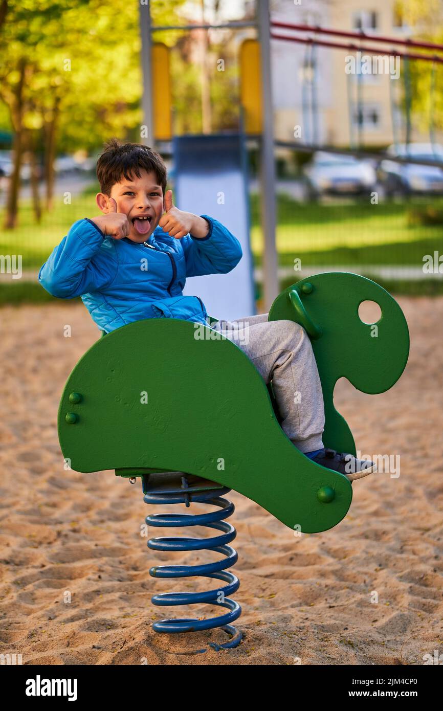 A child sitting on fish-shaped wooden swing equipment at a playground ...