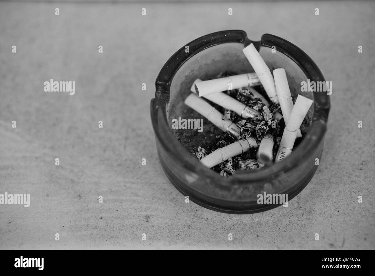 The used cigarette buds laying in a full ashtray Stock Photo - Alamy