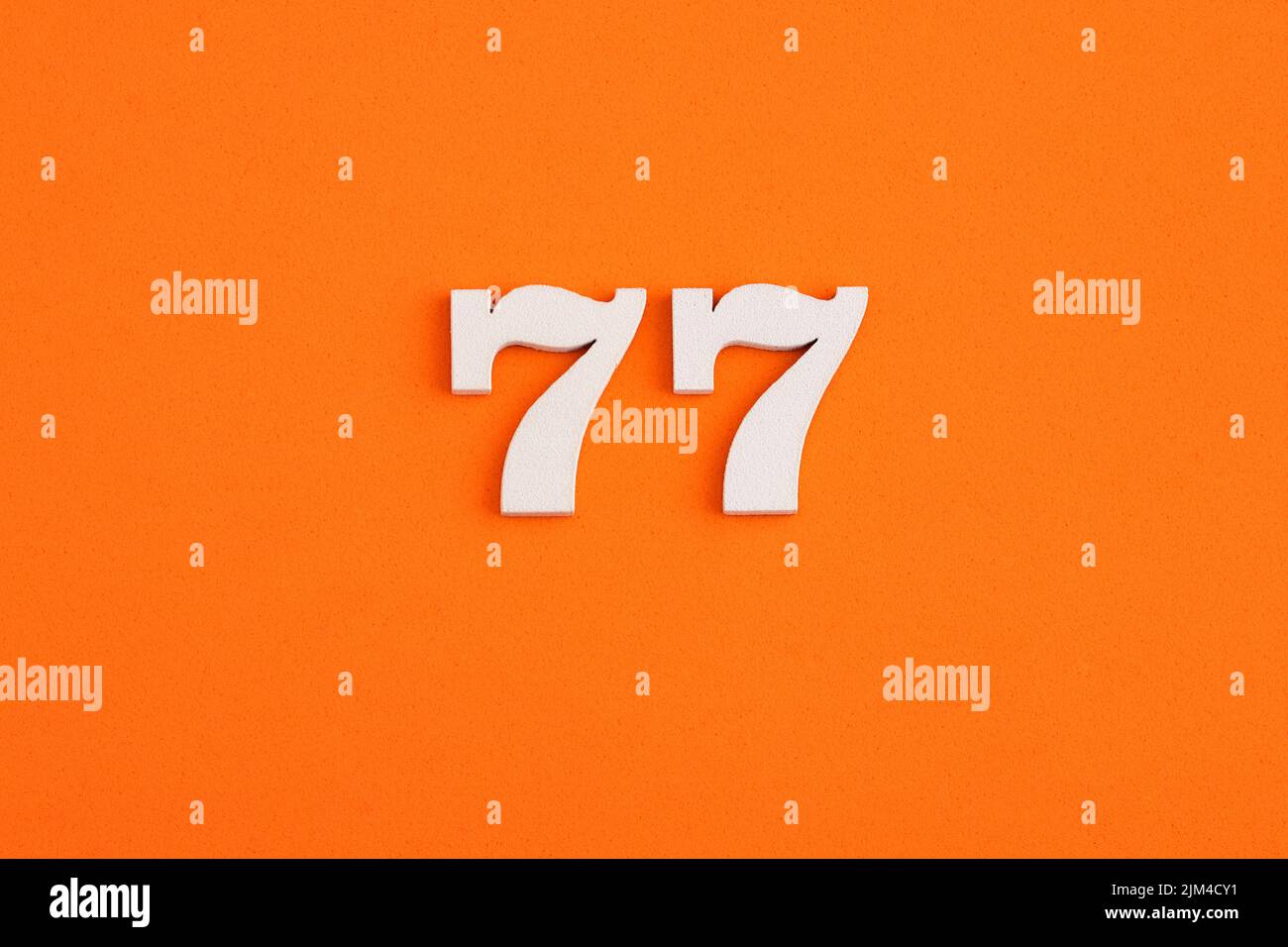 Number 77 - On orange foam rubber background Stock Photo - Alamy