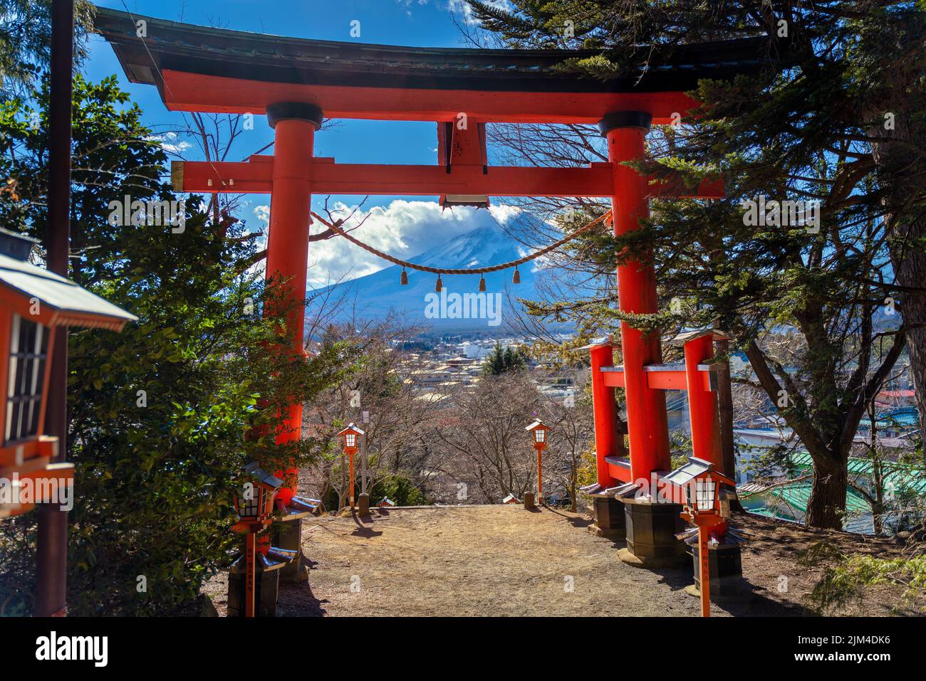 The torii gate surrounded by trees against Mount Fuji and the blue sky ...