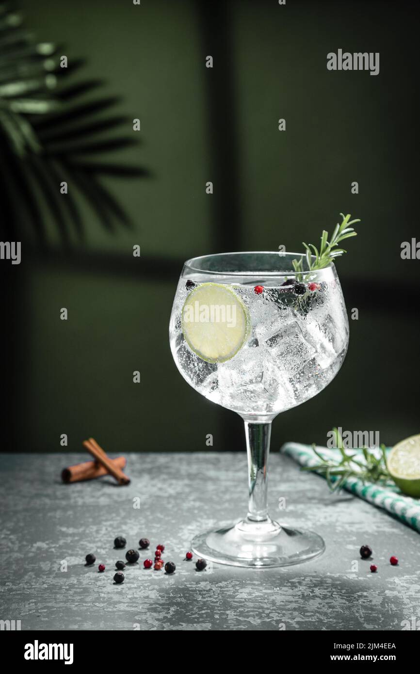 Gin tonic cocktail and shadows next to the window on dark concrete ...