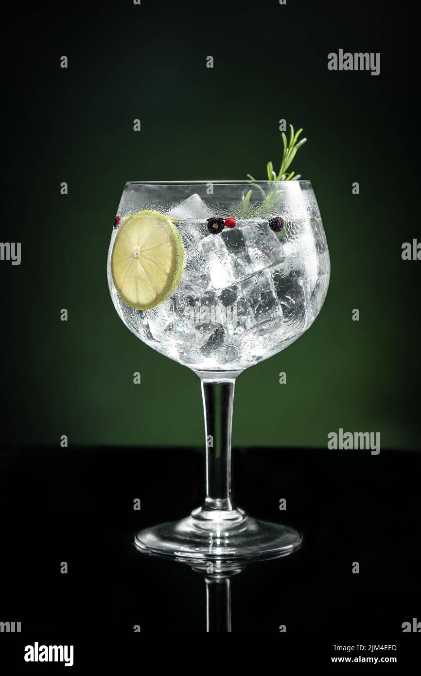 Cold glass of gin tonic with ice on dark green background with copy ...