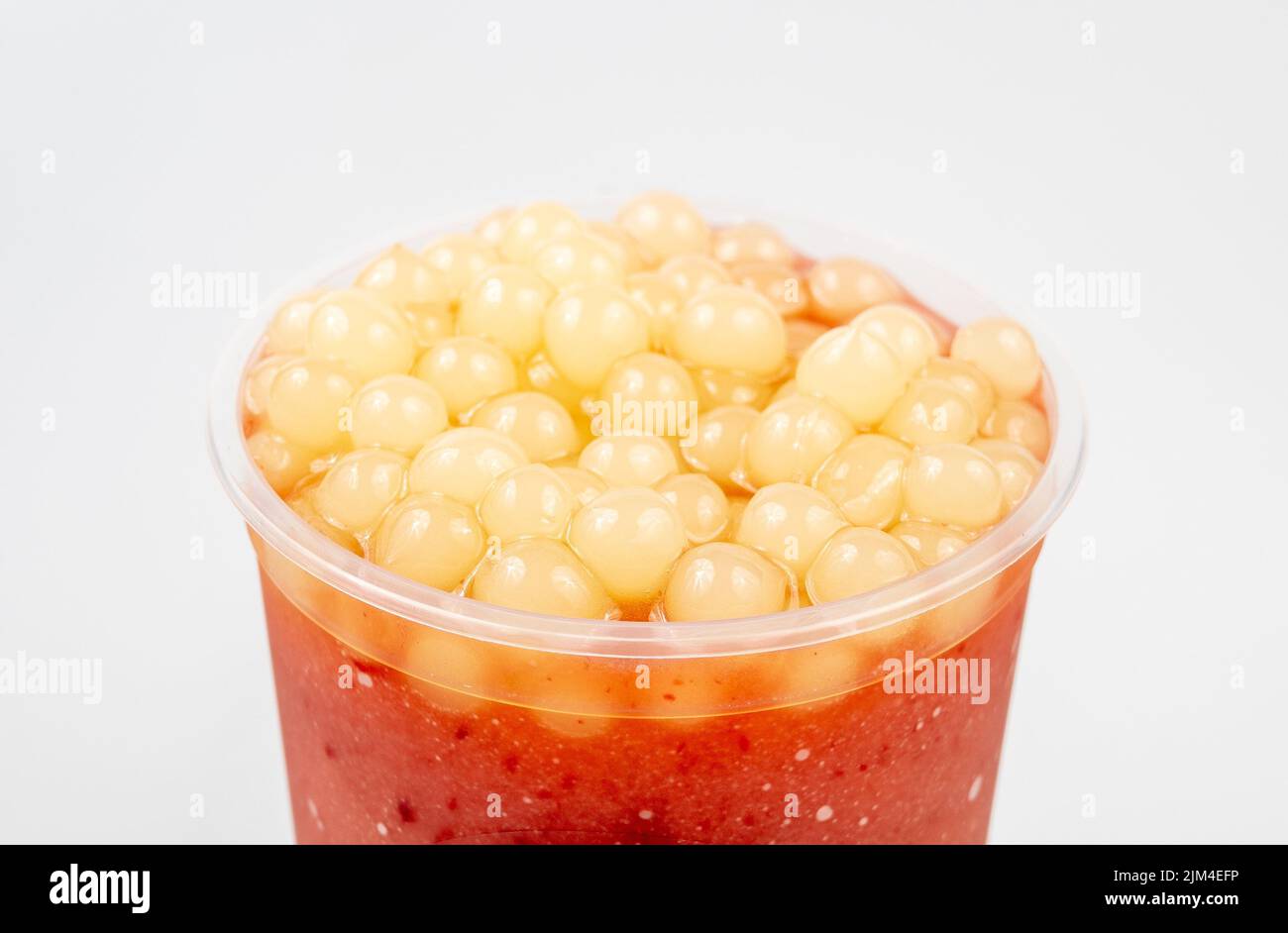 A closeup of a cup filled with delicious orange bubble tea with cream ...