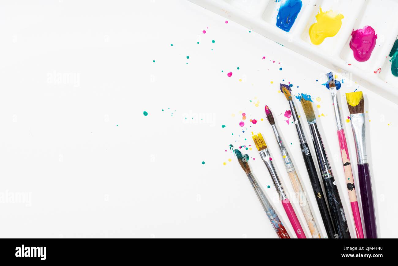 Art Paint brushes and palette with colorful paint splatter on white ...