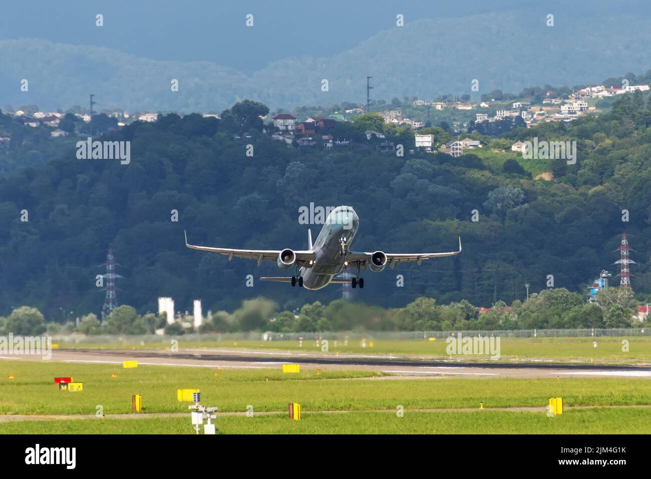 Passenger airliner take off against the backdrop of hills and buildings ...