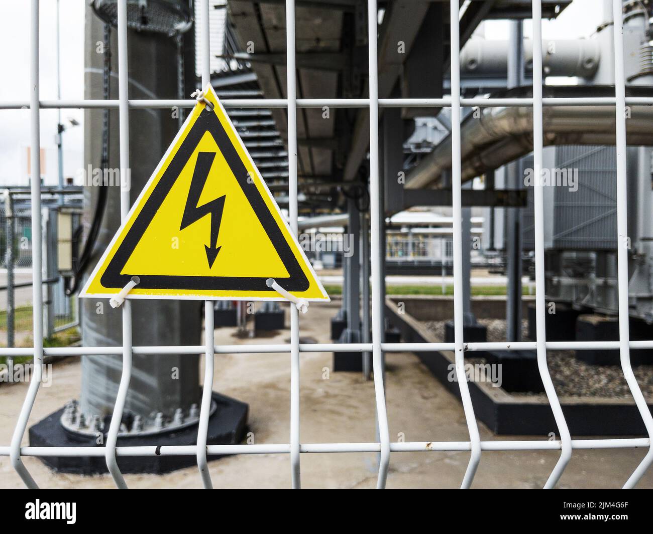 Danger Sign High voltage in the yellow triangle on the metal fence of ...