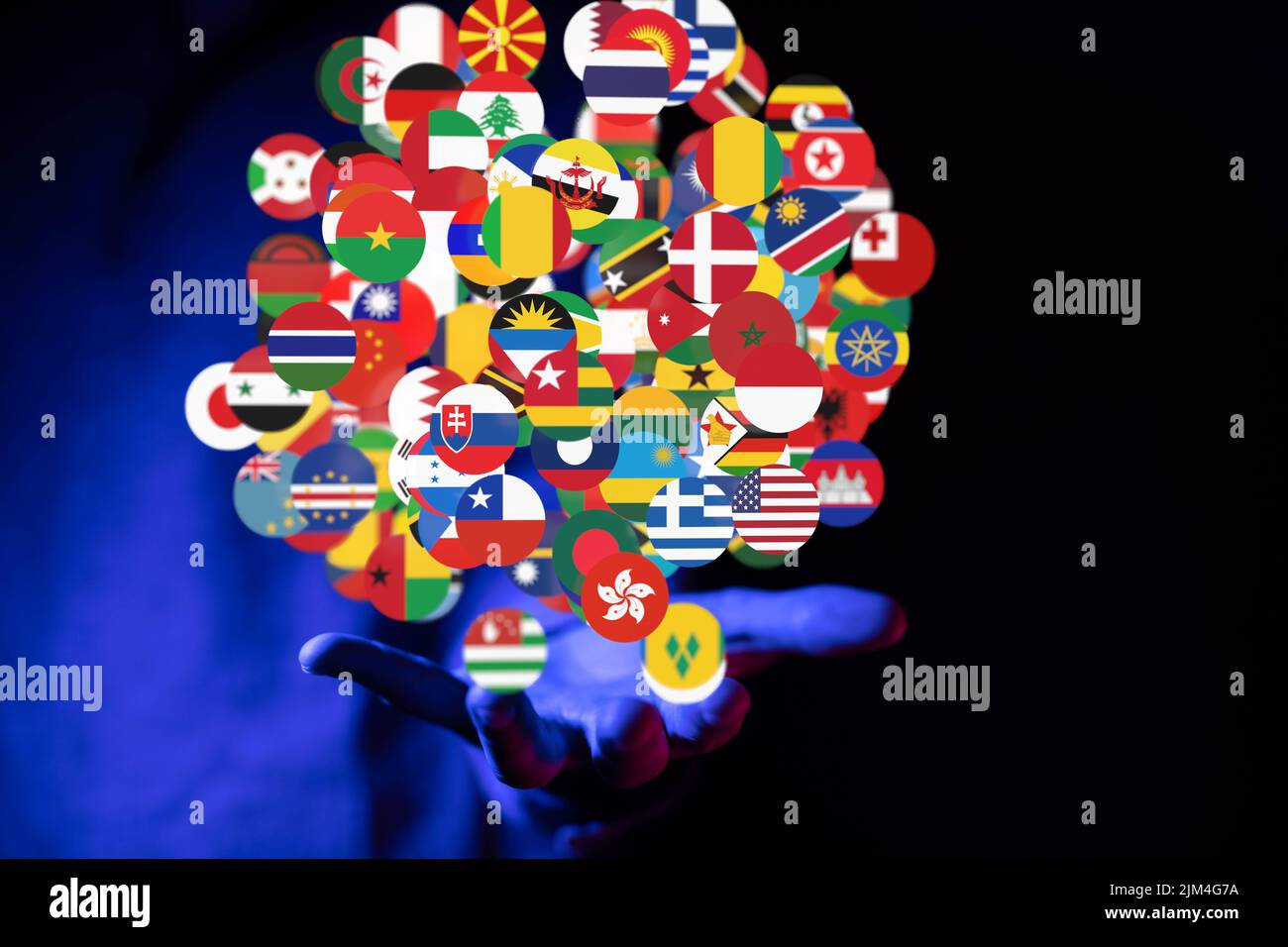 A hand holding illustrated flags of various countries on a dark ...