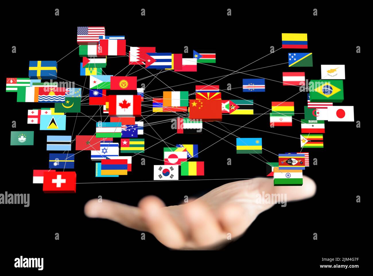 A hand holding illustrated flags of various countries on a dark ...