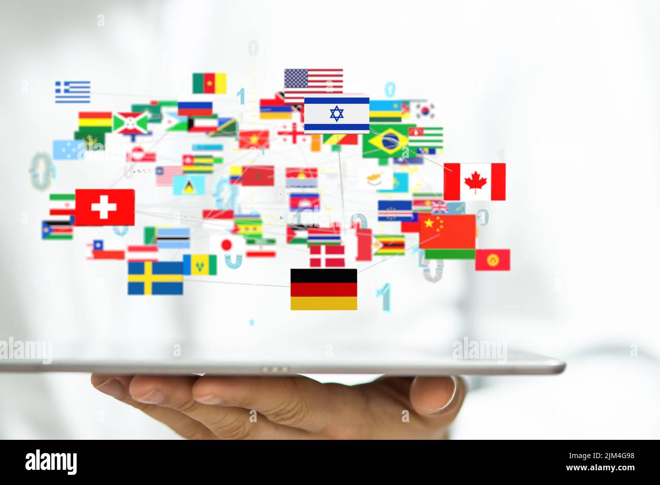 A hand holding illustrated flags of various countries above a tablet ...