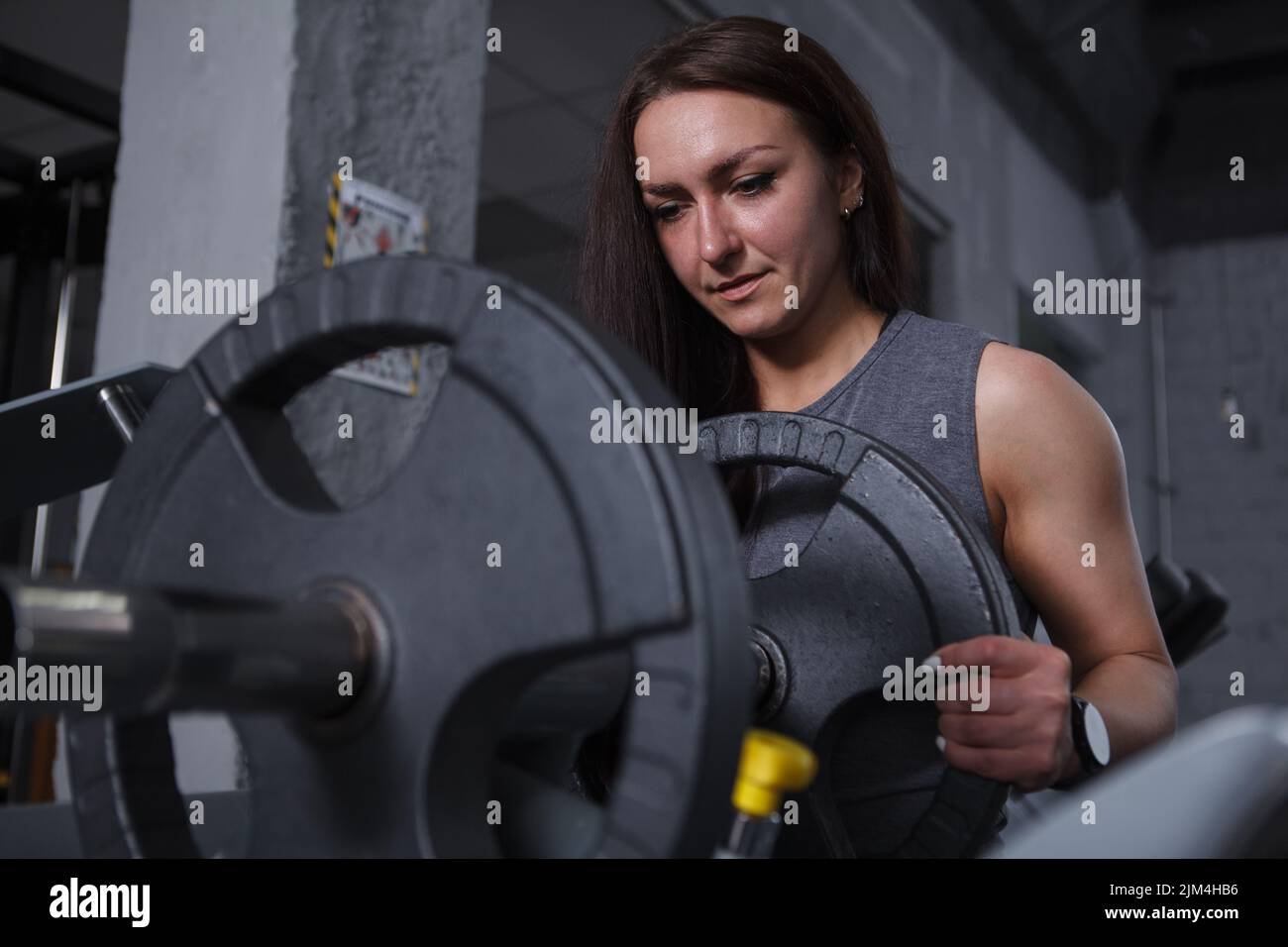 Sportswoman adding weights on leg press machine for her workout Stock ...