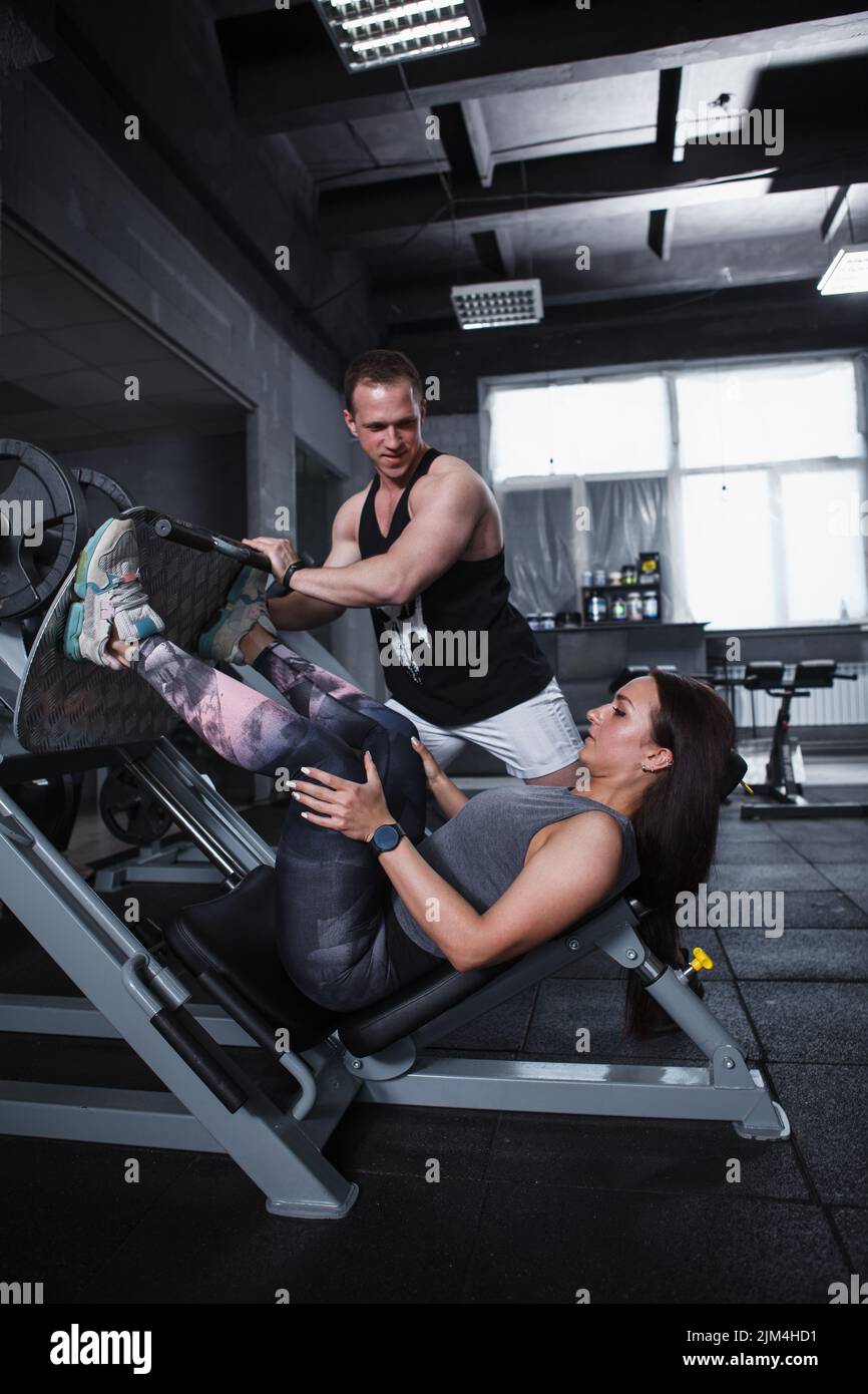 Vertical shot of a professional personal trainer assisting his female ...