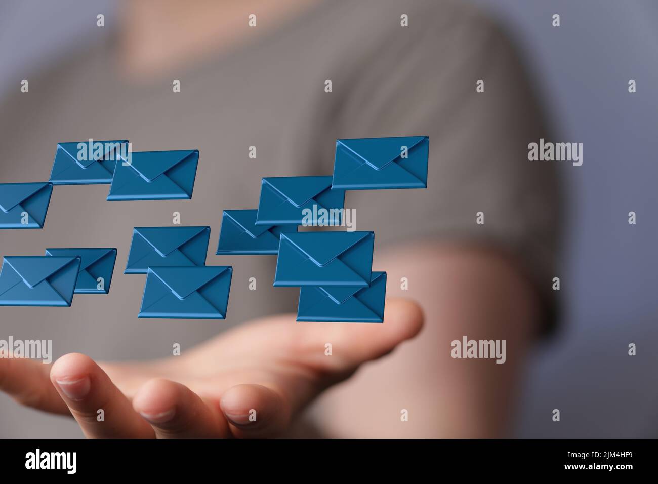 A many blue email icons in a male hand with blurred male background ...