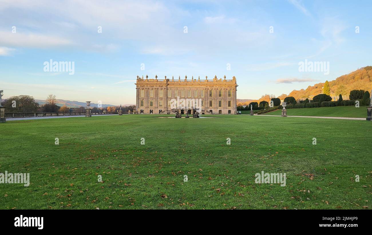 A beautiful view of the Chatsworth House in a green field in England ...
