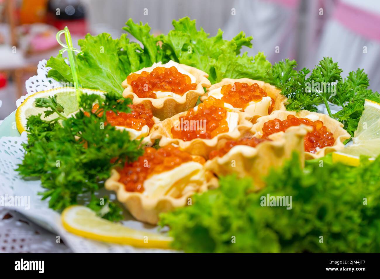 Red caviar and grated cheese in small dough baskets. A delicious cold ...