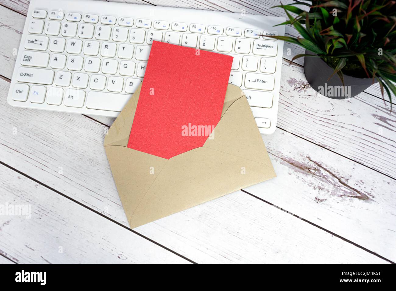 Red note inside brown envelope with keyboard and potted plant ...