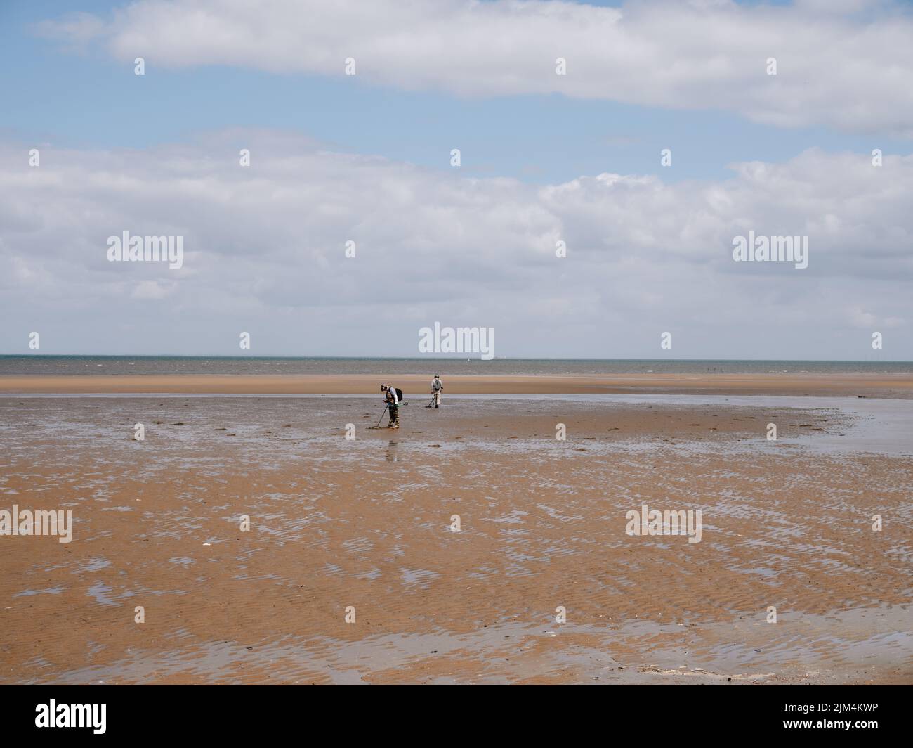 Two metal detectorists working on Hunstanton beach coastline landscape ...