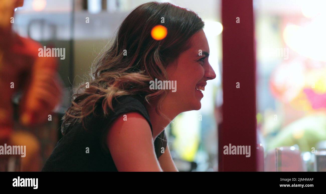 Candid casual young woman seen through window at restaurant speaking to ...