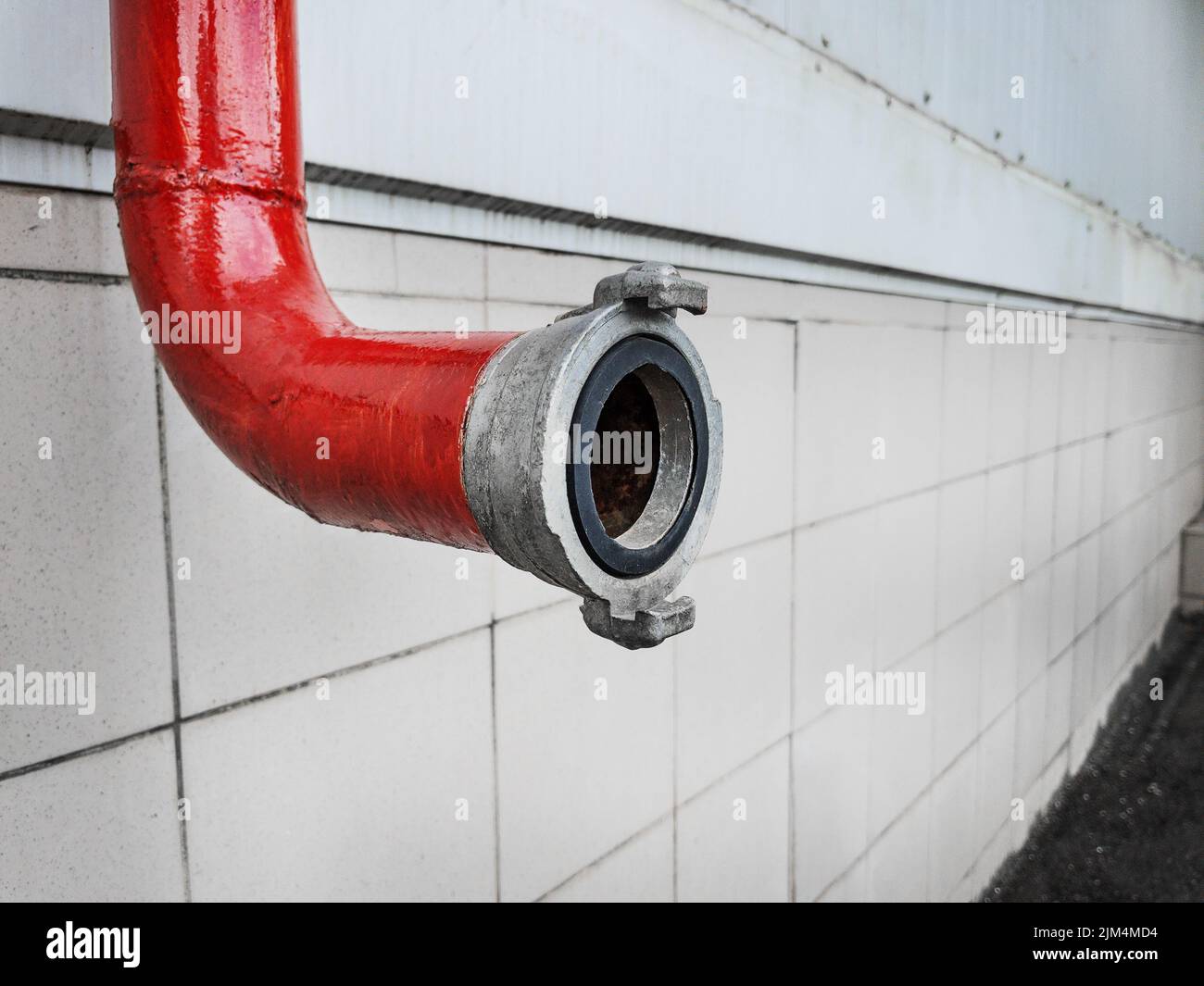 Red fire-fighting pipeline with a lock close-up on a tile background ...