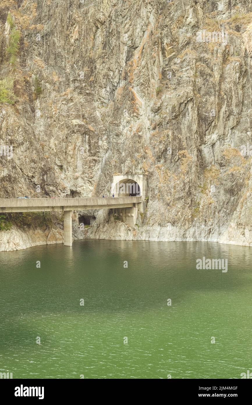 A vertical shot of a tunnel at the Vidraru dam with a reservoir lake in ...