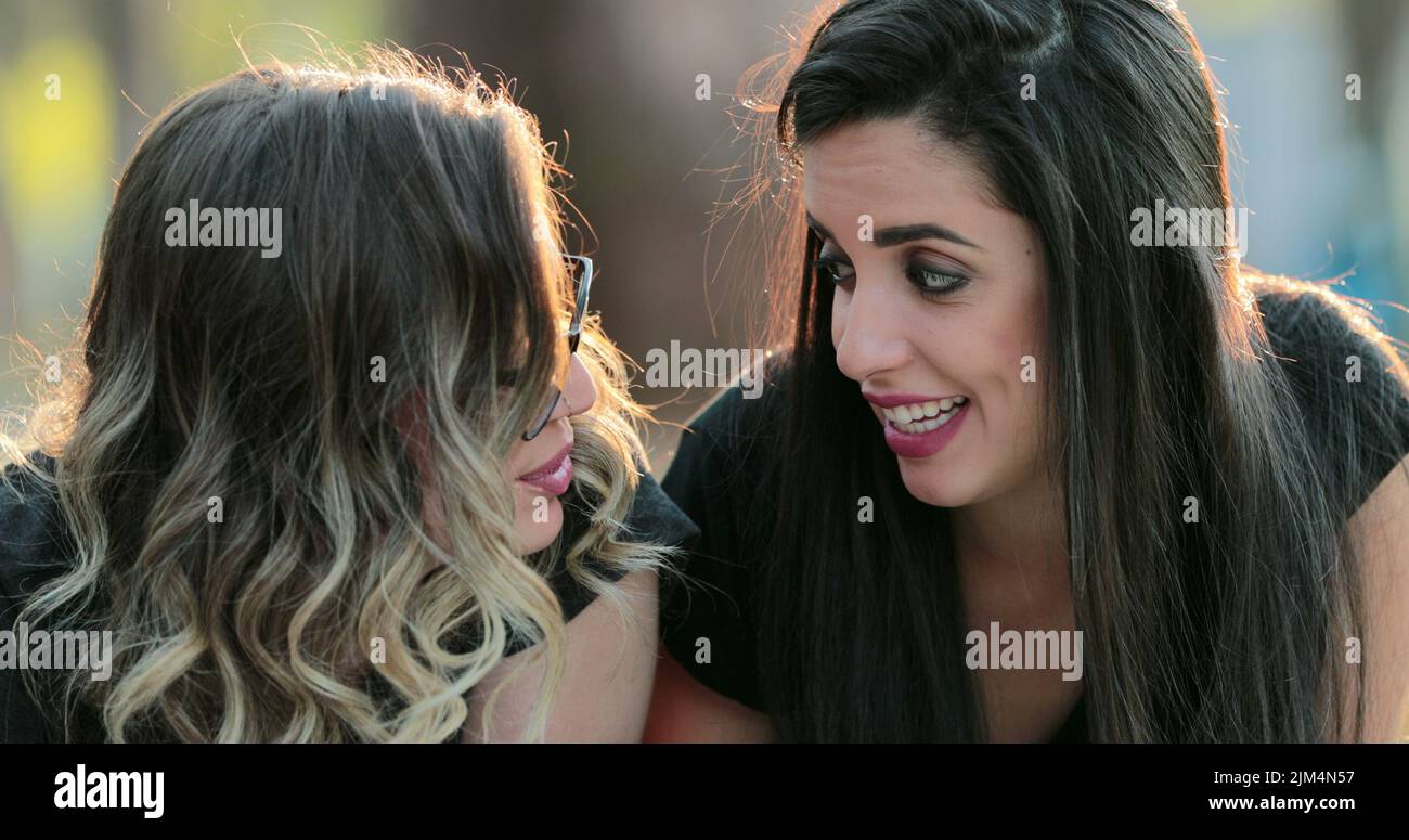 Friends gossiping talking to each other in conversation outside in the ...