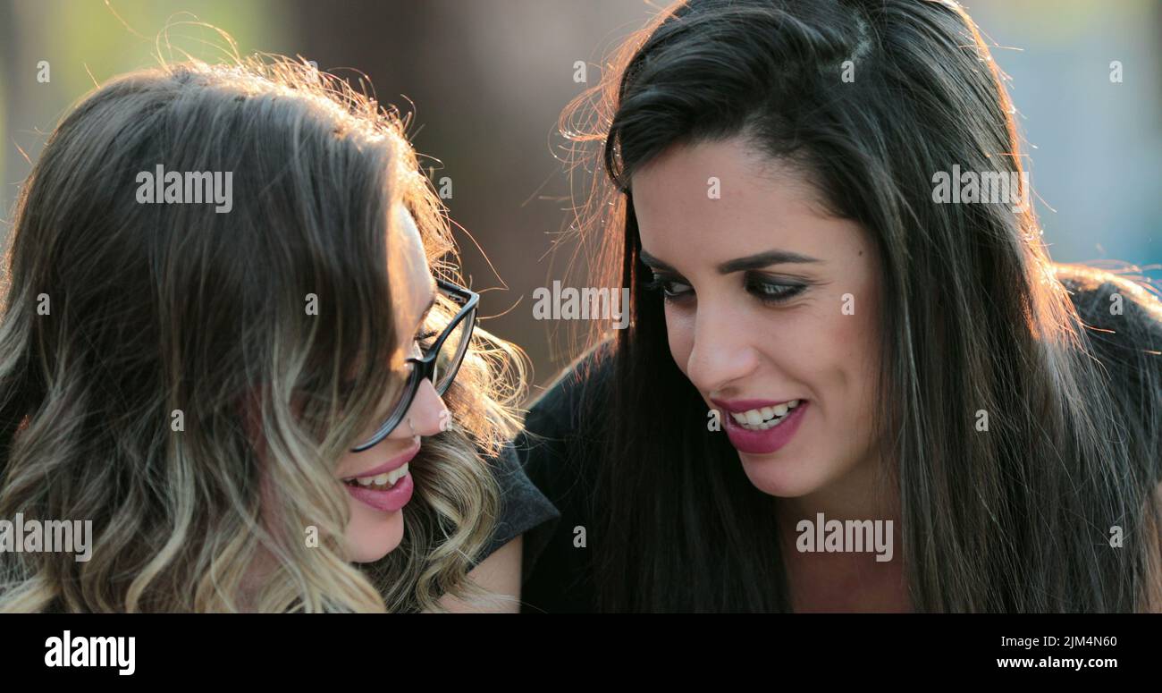 Friends gossiping talking to each other in conversation outside in the ...