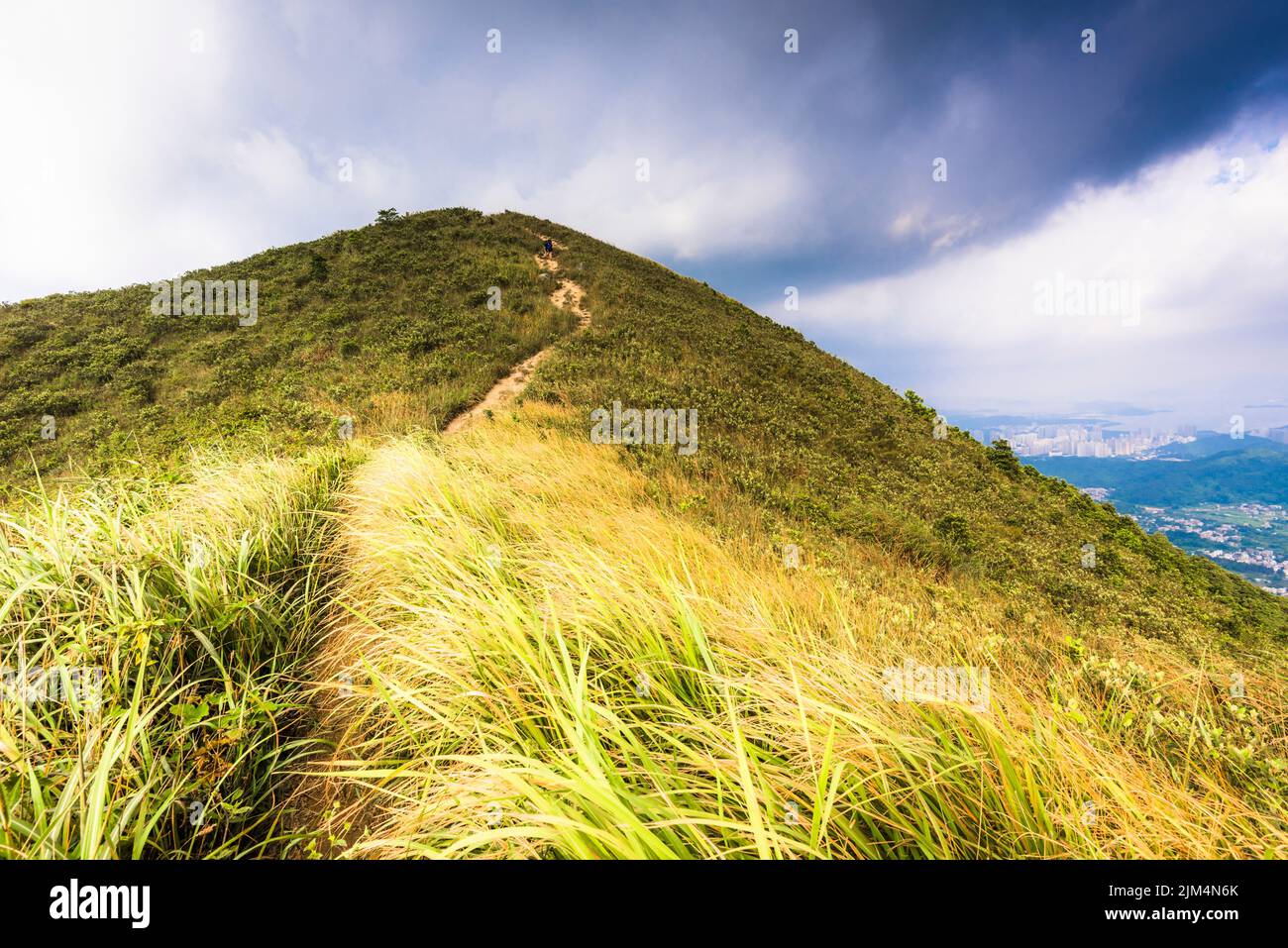 Closeup of a narrow path on a mountain peak with grass and lands in the ...