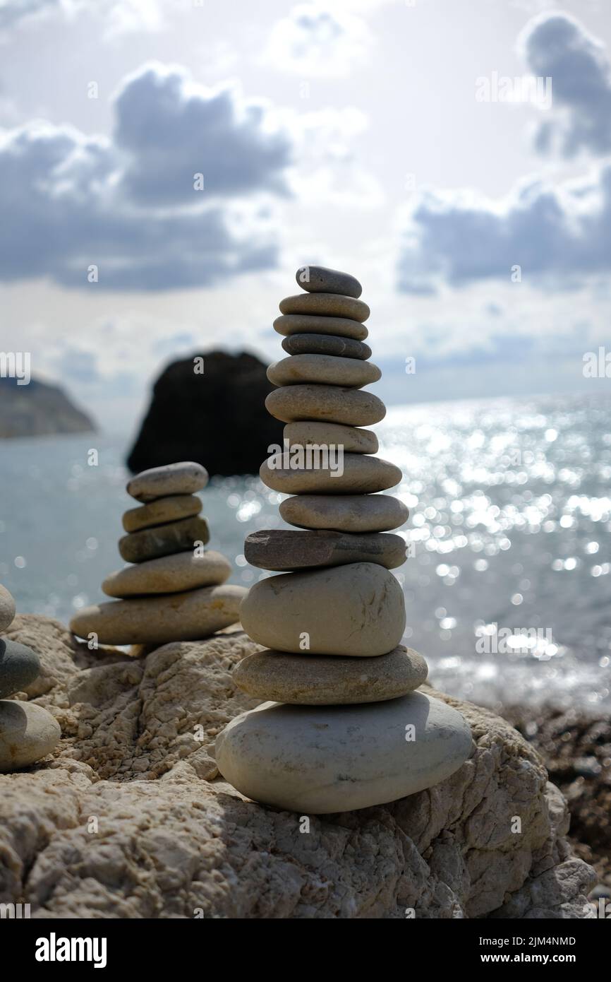 A vertical shot of a pyramid of stones on the rocky shore of the bay ...