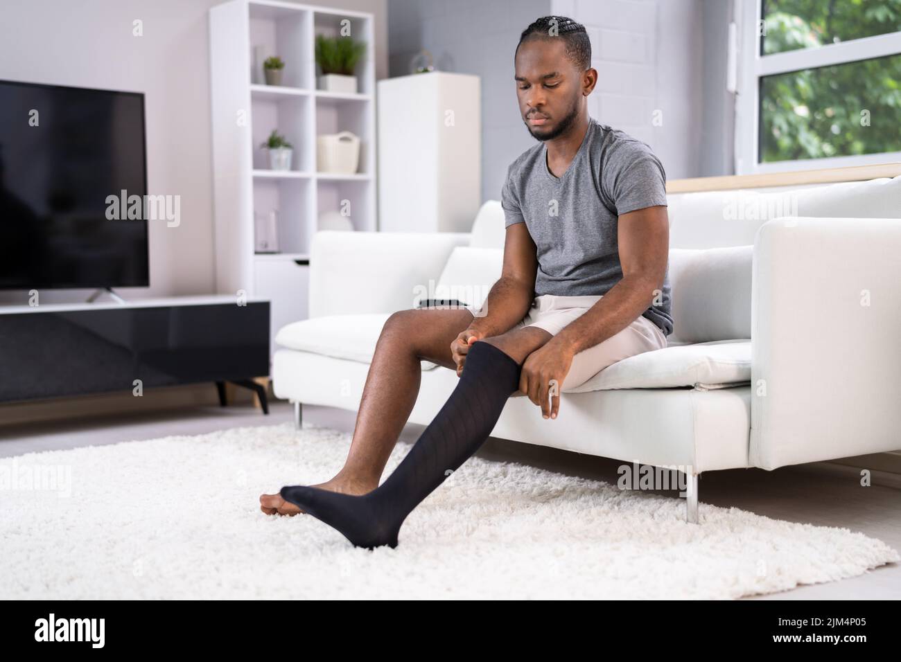 Man Putting On Medical Compression Stockings On Legs Stock Photo - Alamy