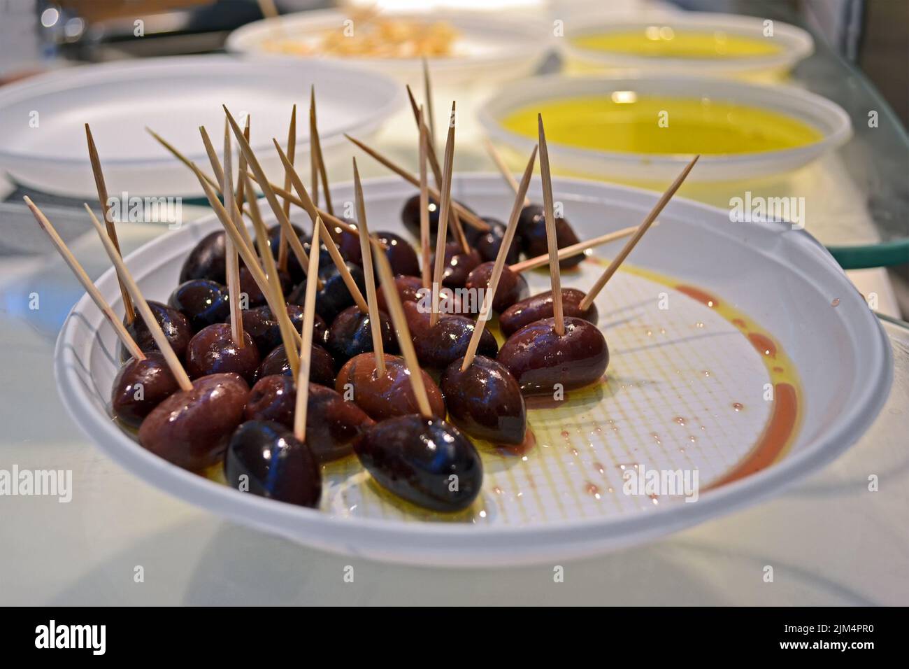 violet olives heap in oil on the white plastic plate closeup, delicious ...