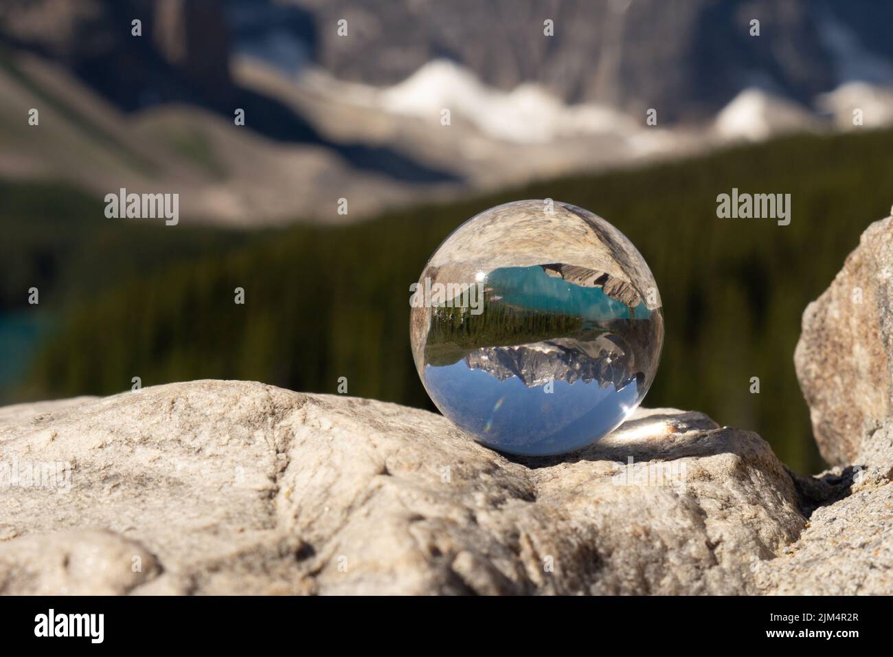 A shallow focus shot of a glass ball on a rock reflecting landscape ...