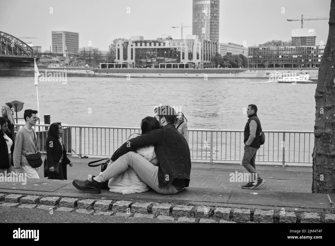Young couple in love hugging, sitting on the banks of the Rhine in ...