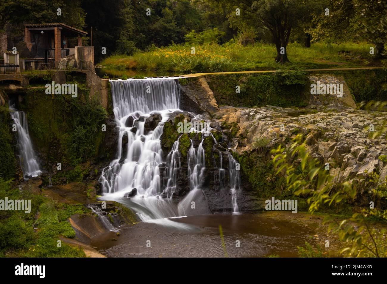 A natural view of a small waterfall flowing downstream in a park Stock ...