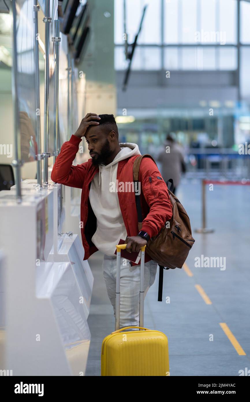 Upset African man standing at check-in counter in airport, being sad ...