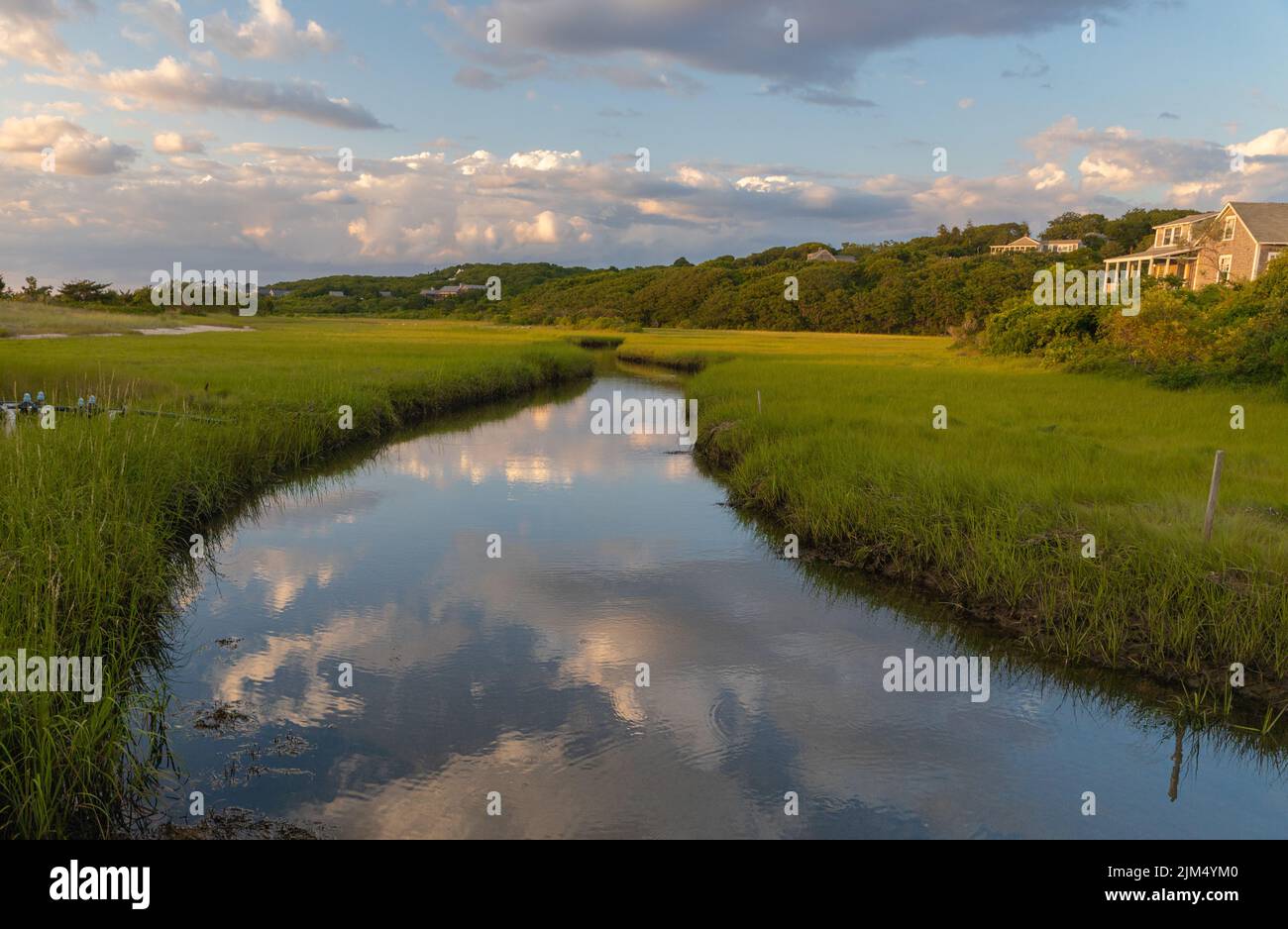 An evening reflection of a creek running through a marsh by the ocean ...