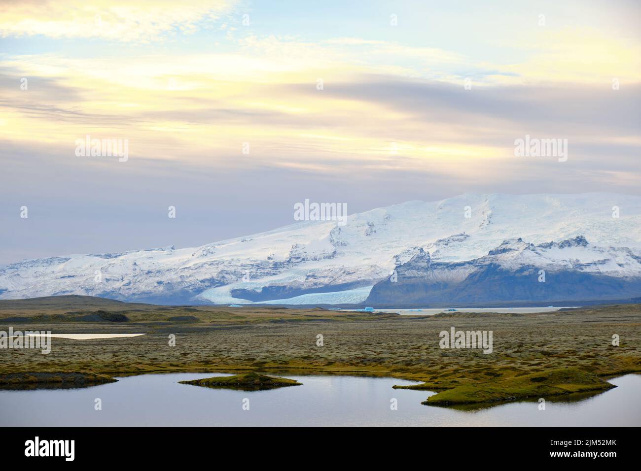 Snow covered mountain behind glacial melt lake Stock Photo - Alamy