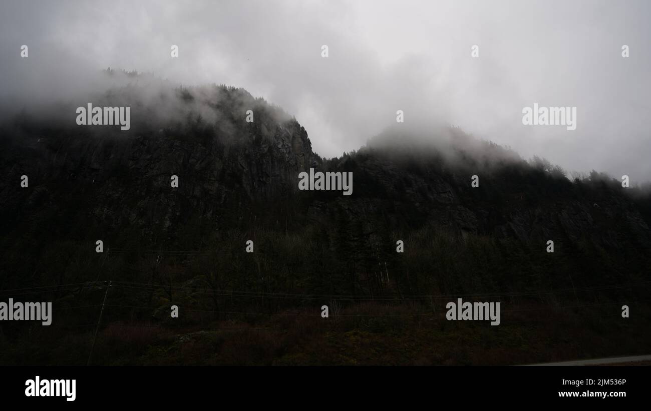An eerie scenery of dark mountains with fog covering the peaks on a ...