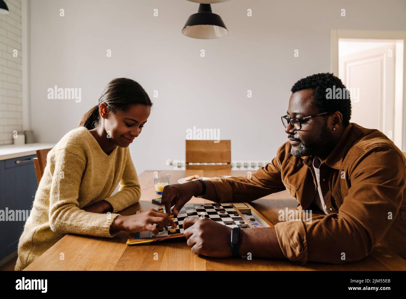 Black girl and her father playing checkers in kitchen at home Stock ...