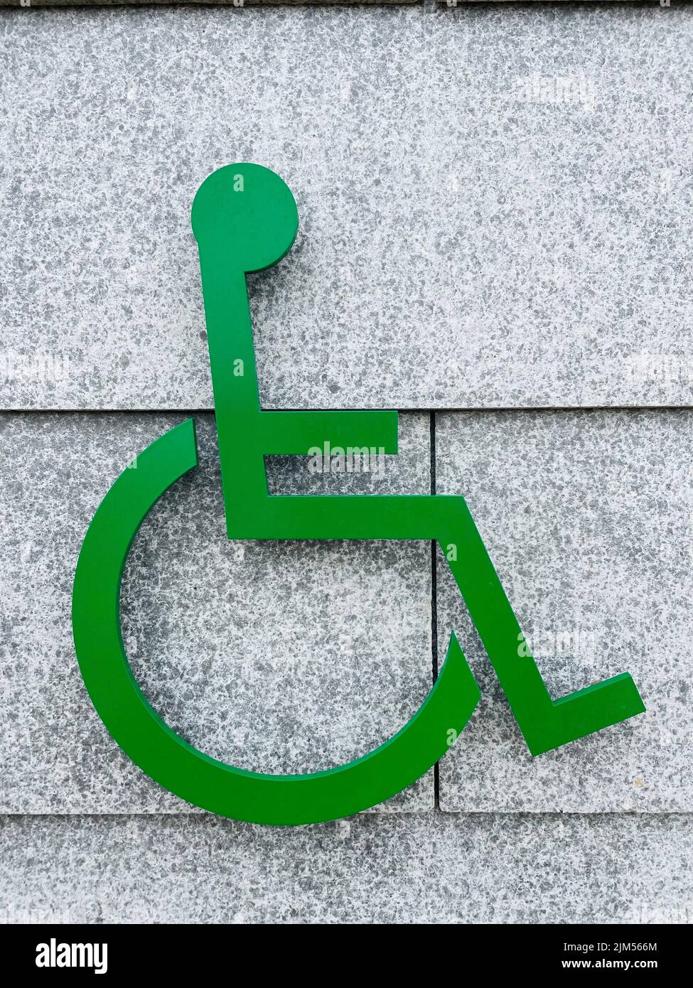 A vertical shot of a green Disability signage on the toilet wall Stock ...