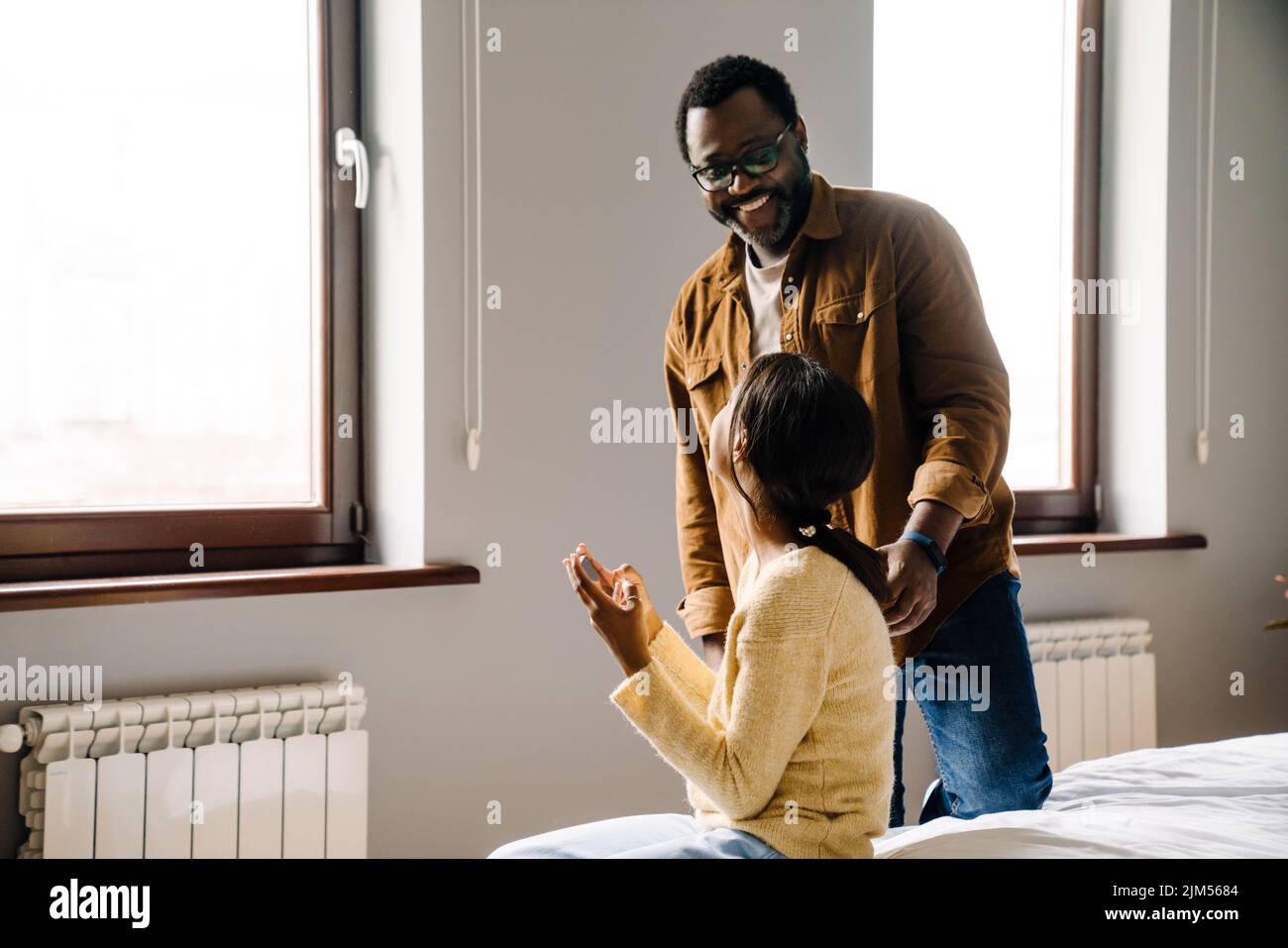 Black girl using cellphone while talking with her father at home Stock ...
