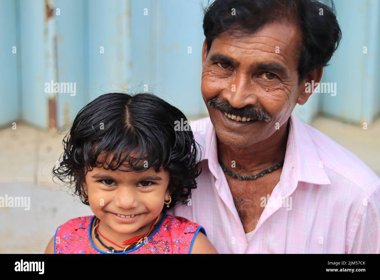 A grandfather carrying his granddaughter holding a balloon in his arms ...