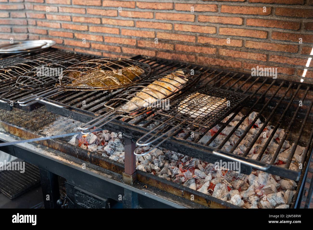 Fresh fish grilling on old charcoal parrillas white fish sea bass and ...